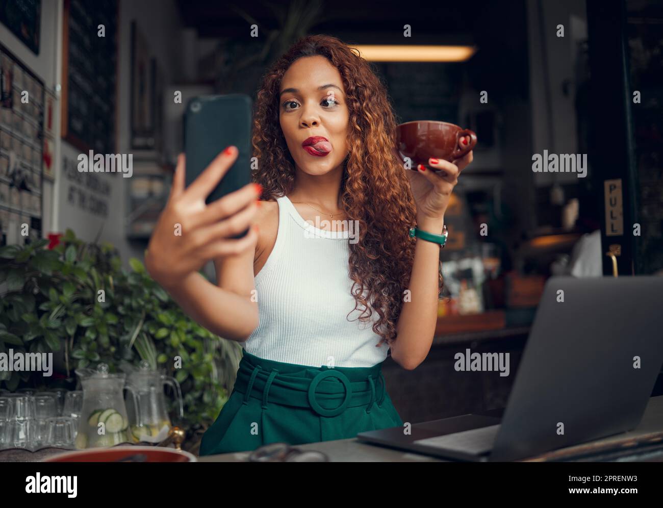 Selfie, coffee shop and funny with a woman customer using a laptop and phone in her local cafe ...