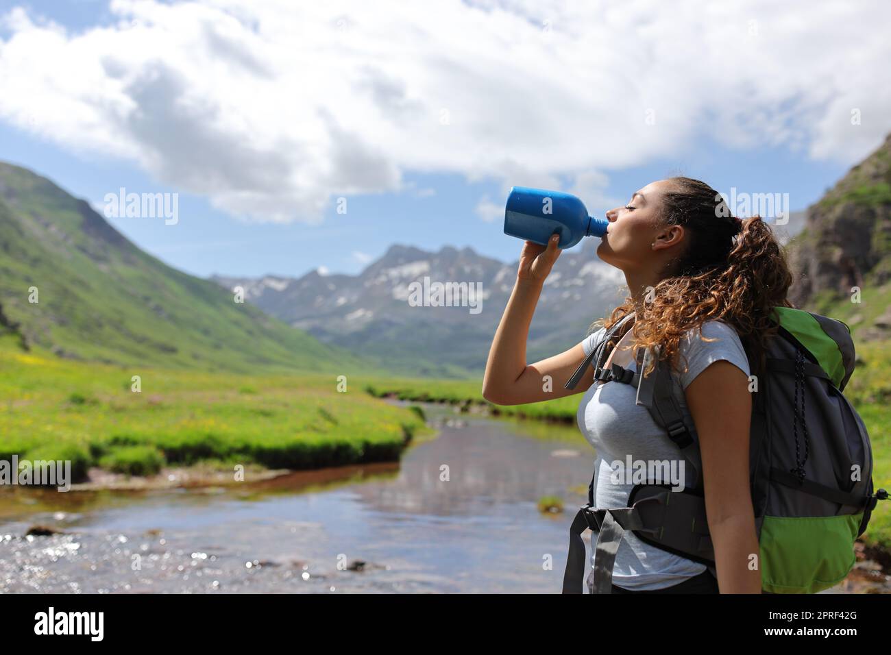 Trekker drinking water from canteen in a river Stock Photo - Alamy