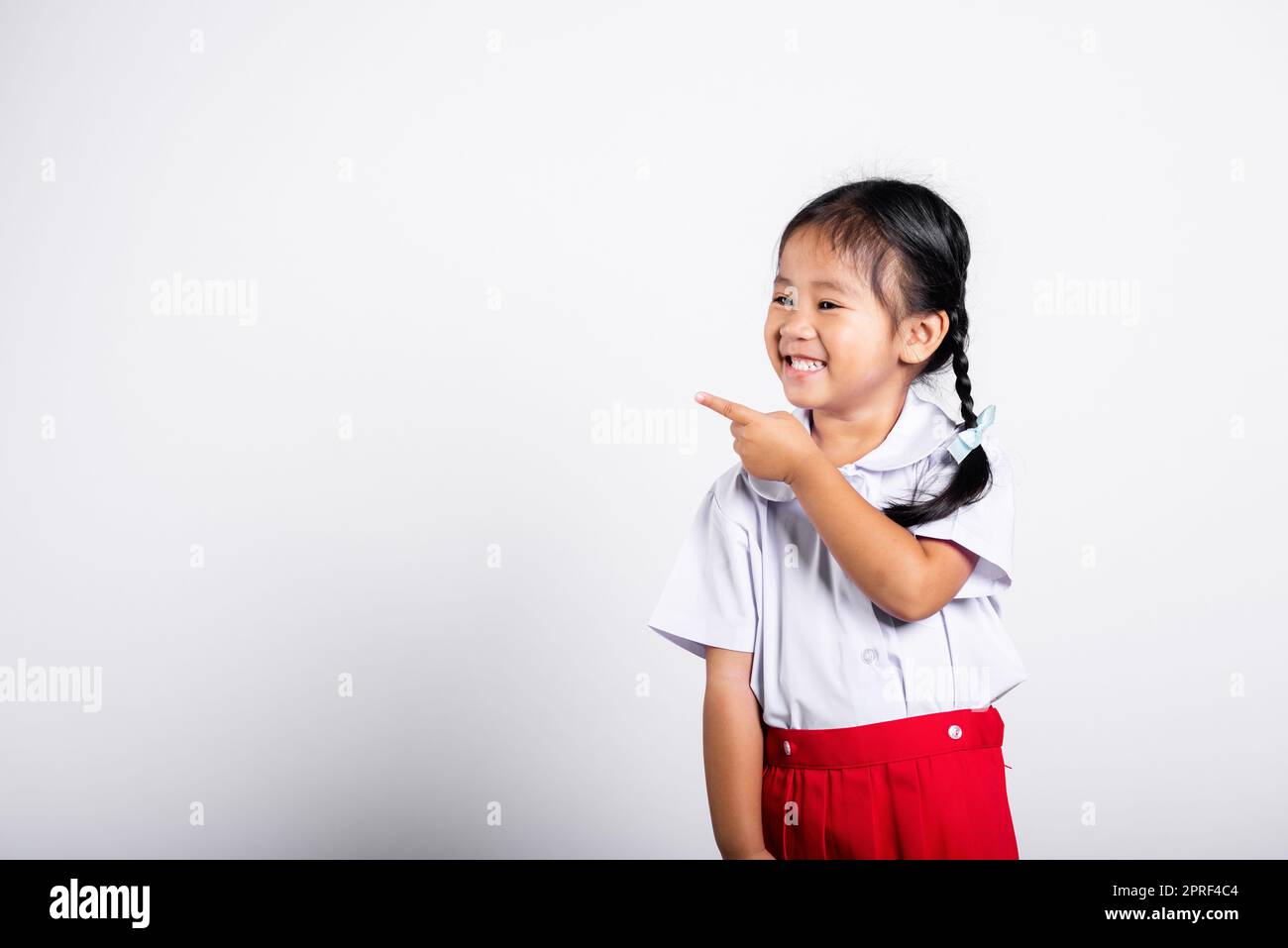Asian toddler smiling happy wear student thai uniform red skirt keeps pointing finger at copy ...