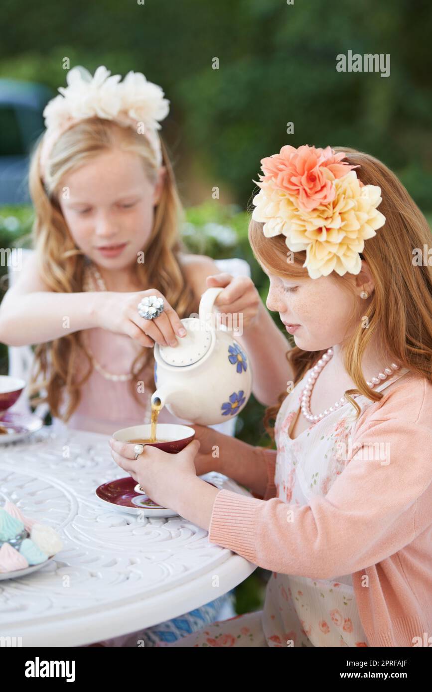 Fancy a spot of tea love. Two young girls having a tea party in the ...