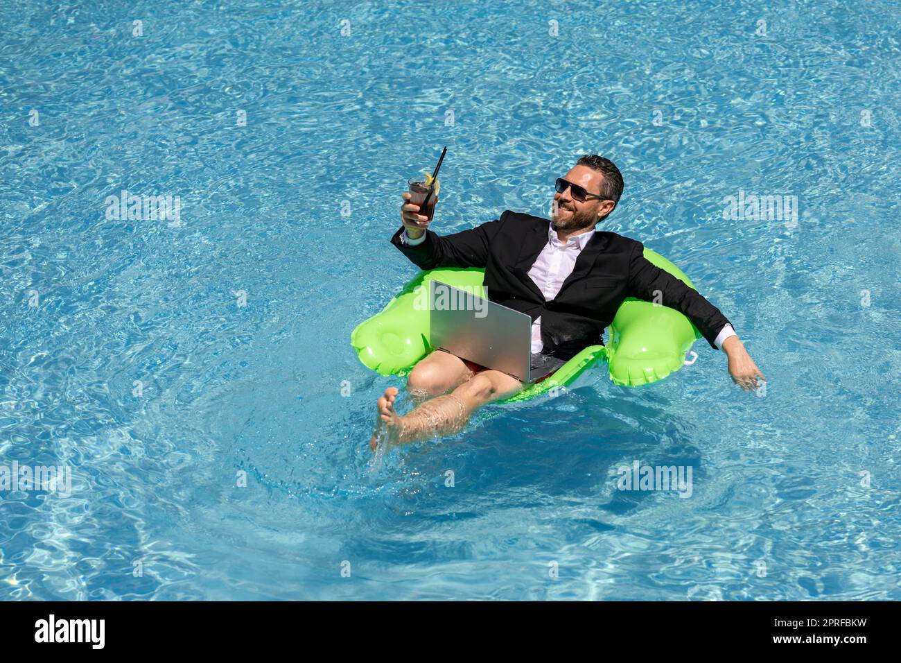Funny business man in a business suit floating in the water in the pool ...