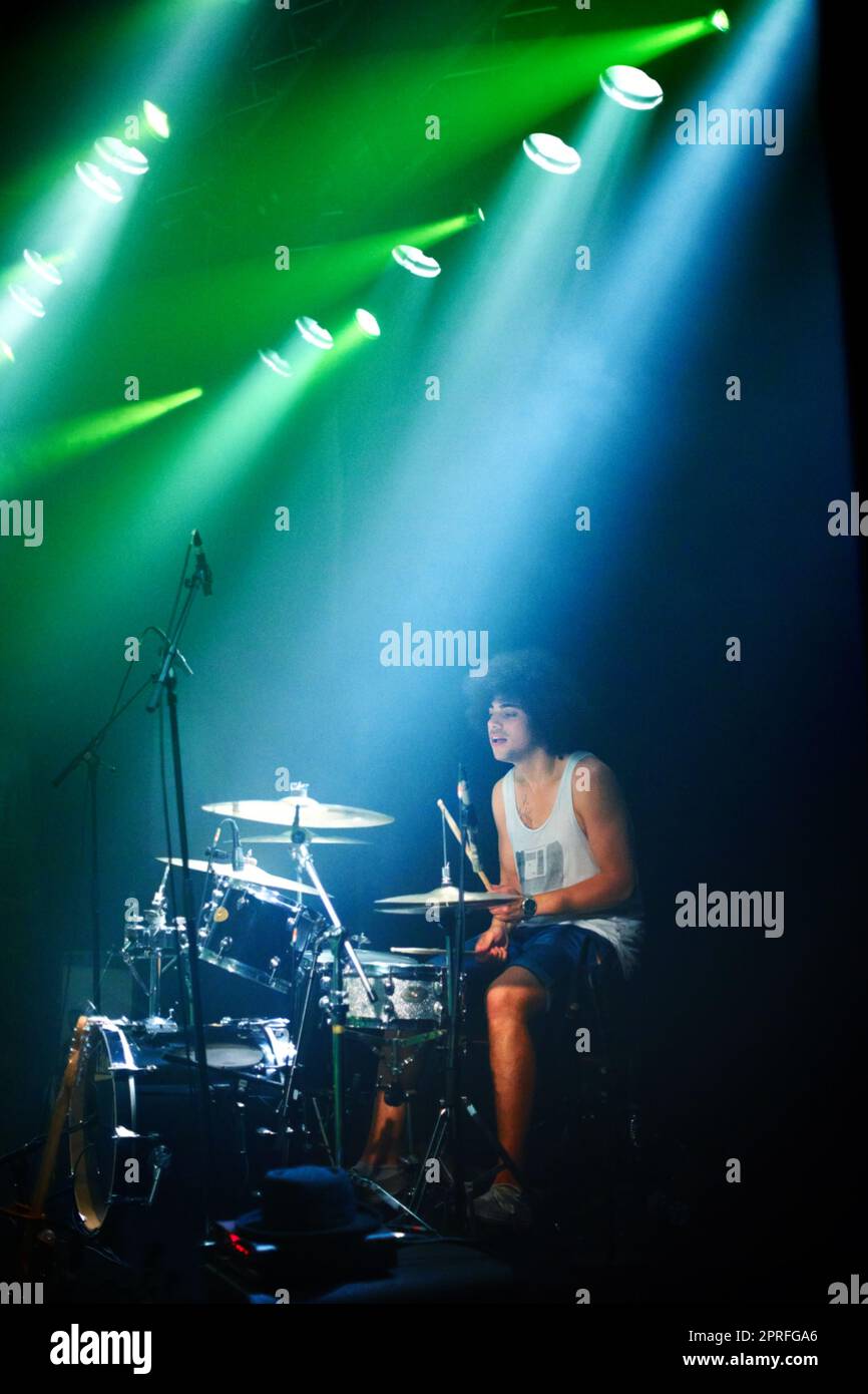 Focused only on the beat. a drummer playing on stage bathed in ...