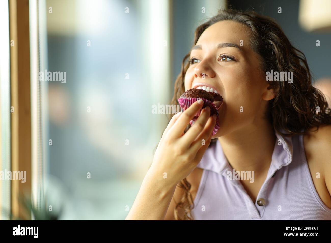 Woman eating chocolate cupcake in a restaurant Stock Photo - Alamy