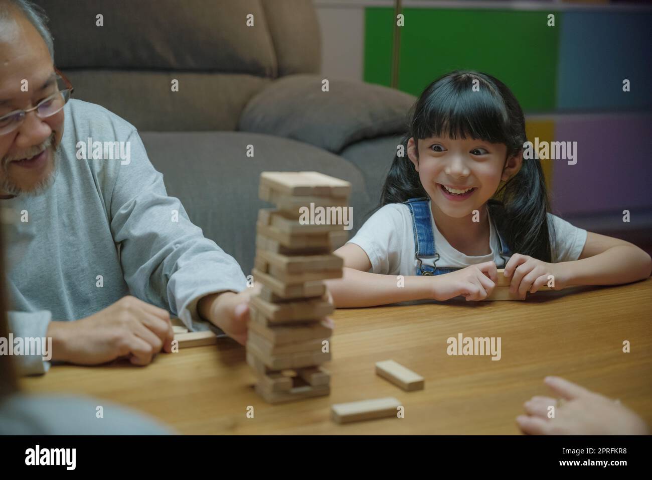 Happy grandparents Asian family enjoy playing toy block with little daughter and mother together ...