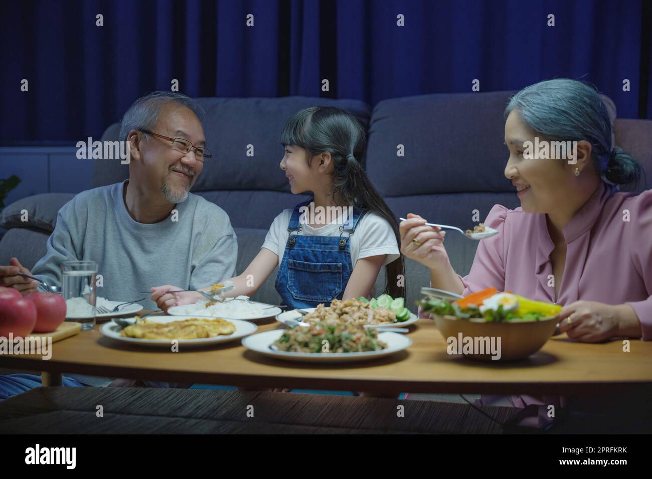 Happy Asian family grandparent and granddaughter dining on table and ...