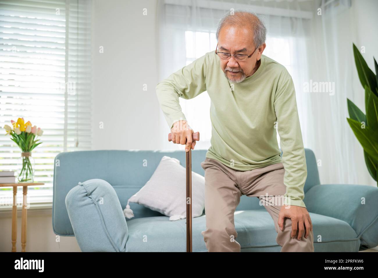 Asian senior old man with eyeglasses type to standing up from sofa with ...