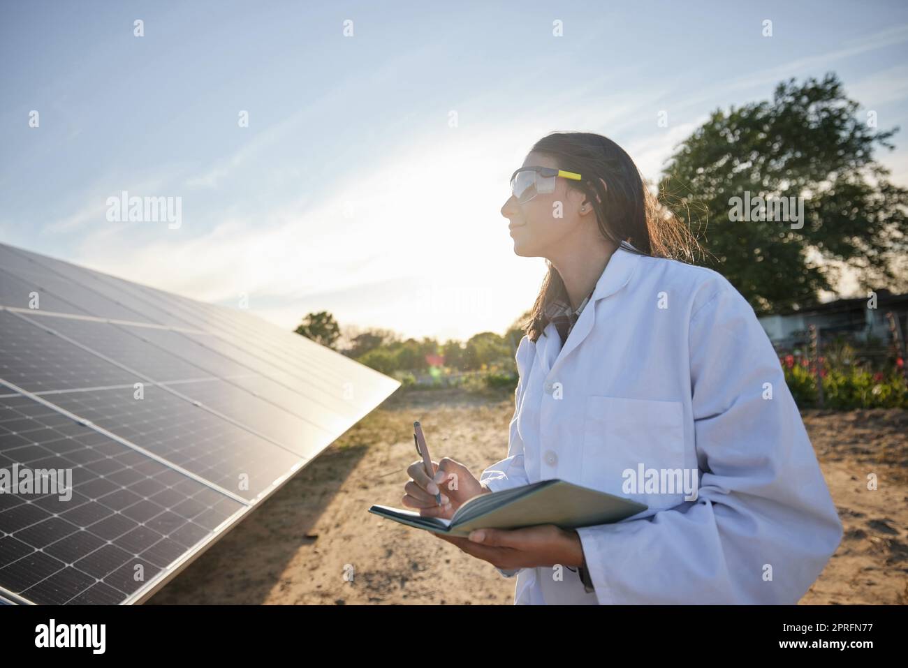 Woman working in solar energy, writing research on solar panels and ...