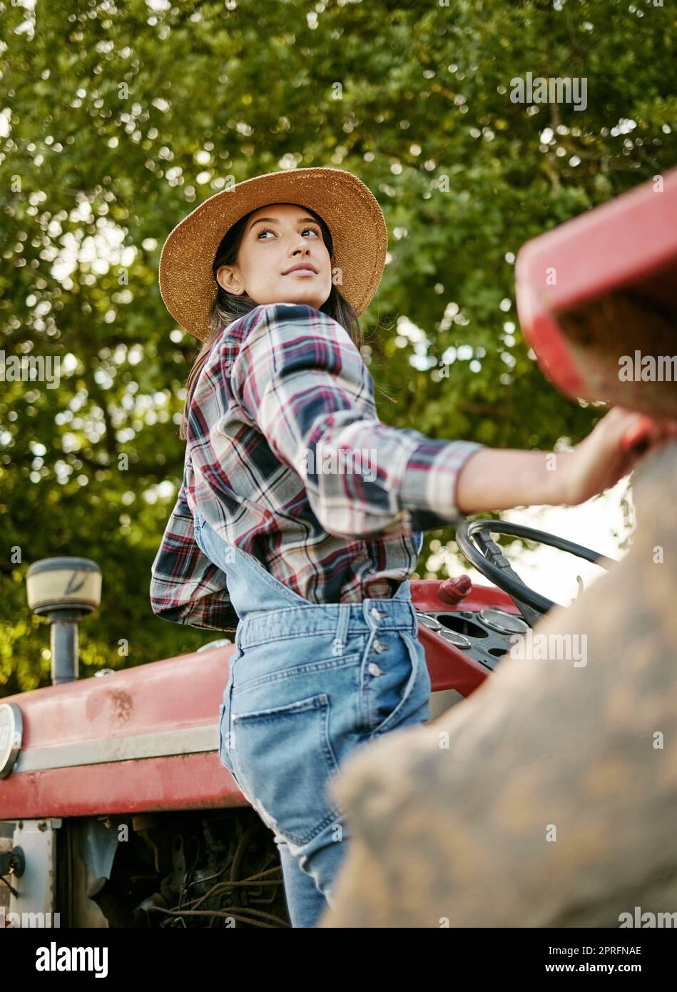 Woman agriculture worker or farmer on tractor working farm during ...