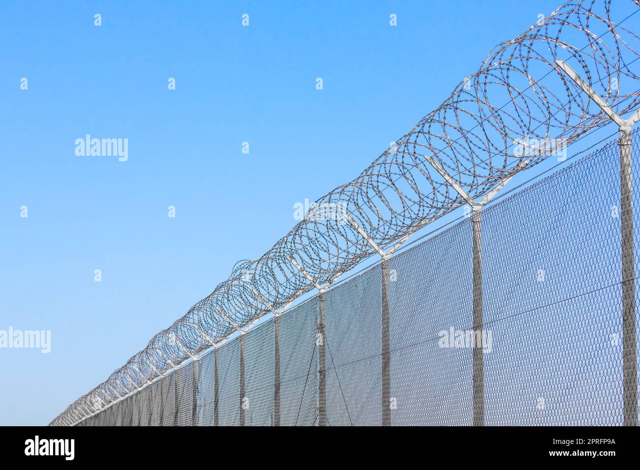 demarcation fence with barbed wire against blue sky Stock Photo - Alamy
