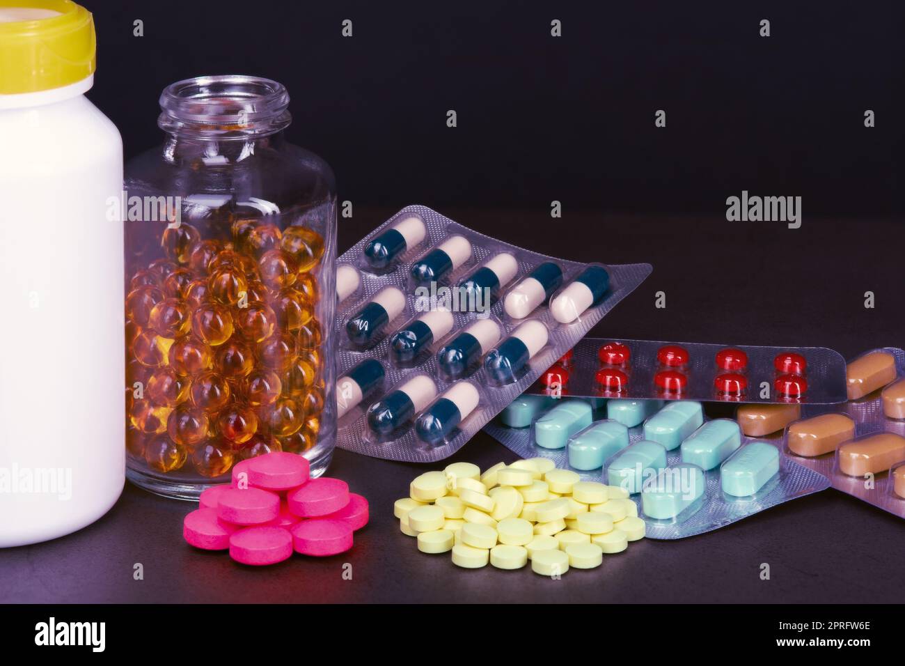 Pills and tablets of different colors are scattered and in bottles on a ...