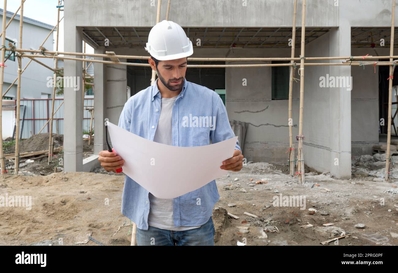 Young engineer in a construction helmet looking at real estate projects ...