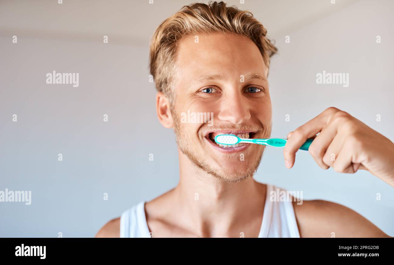 Brush regularly for a winning smile. Portrait of a young man brushing ...
