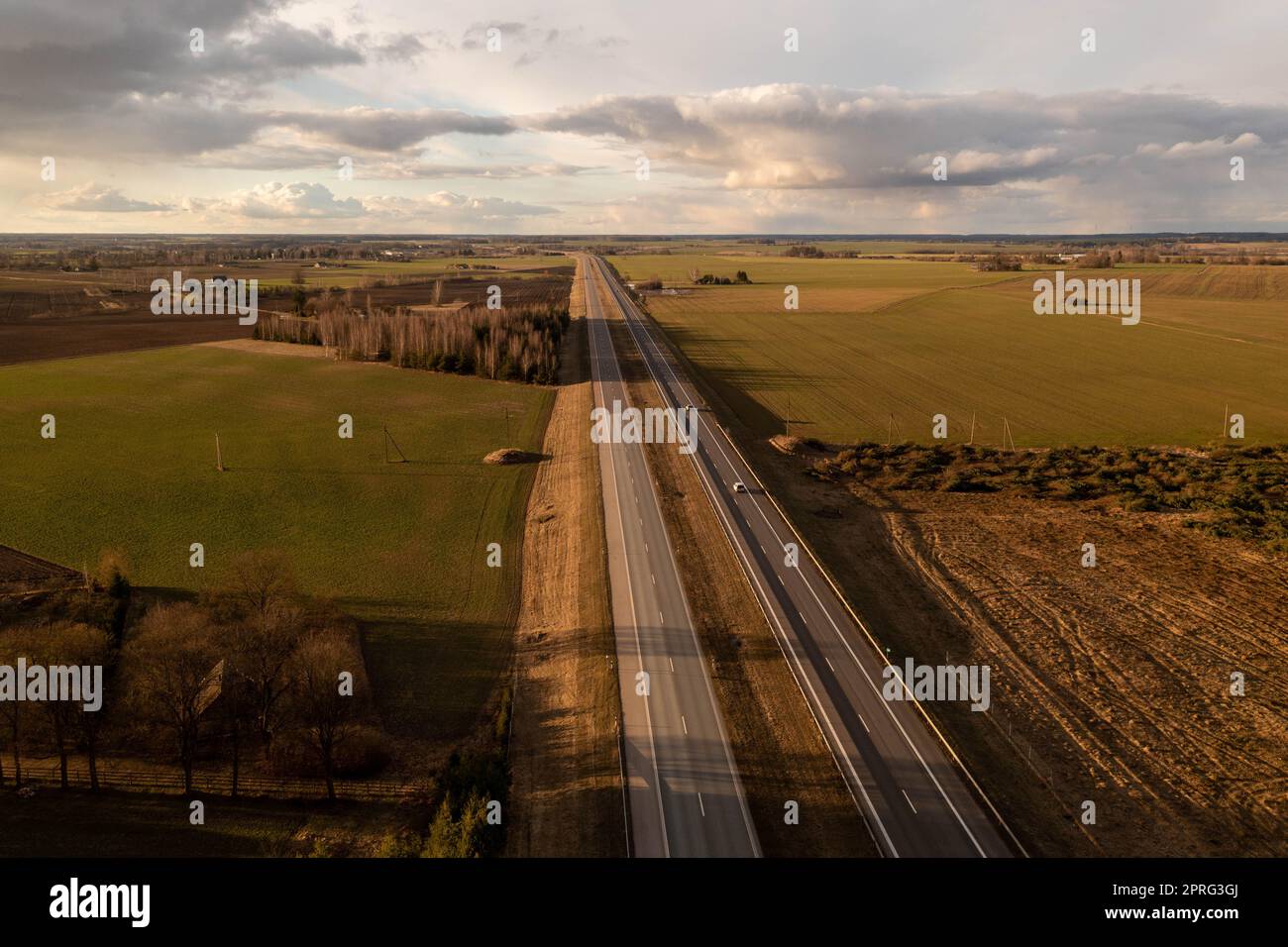 Drone footage of highway surrounded by agriculture fields and forest ...