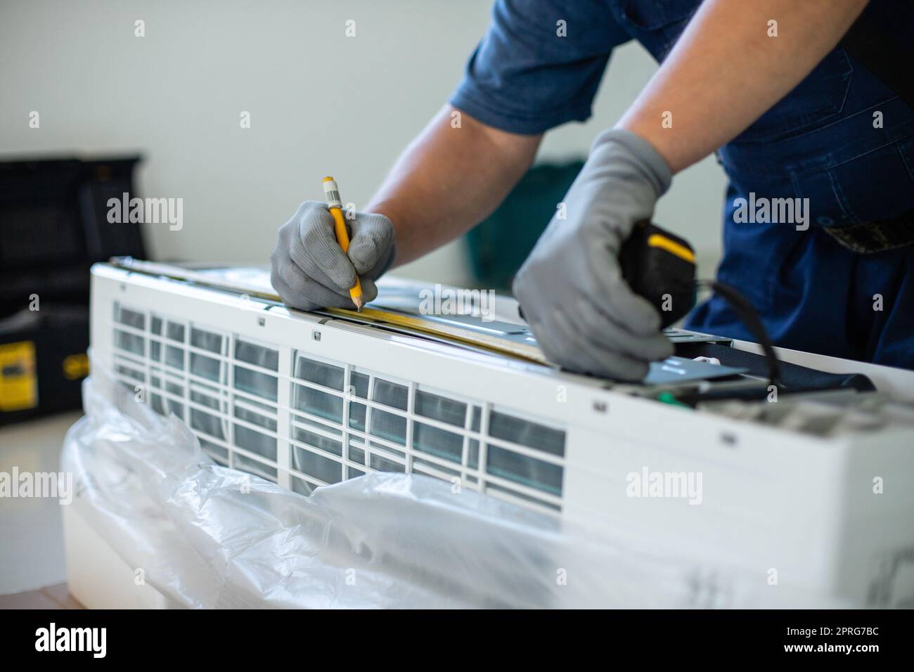 Male technician makes mark with pencil when measuring air conditioner ...