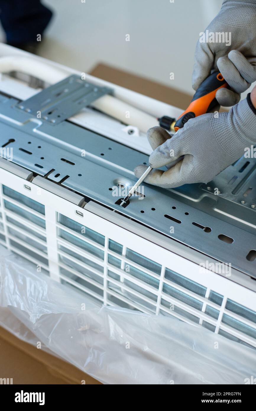Male installer or repairman is going to install air conditioner unit ...