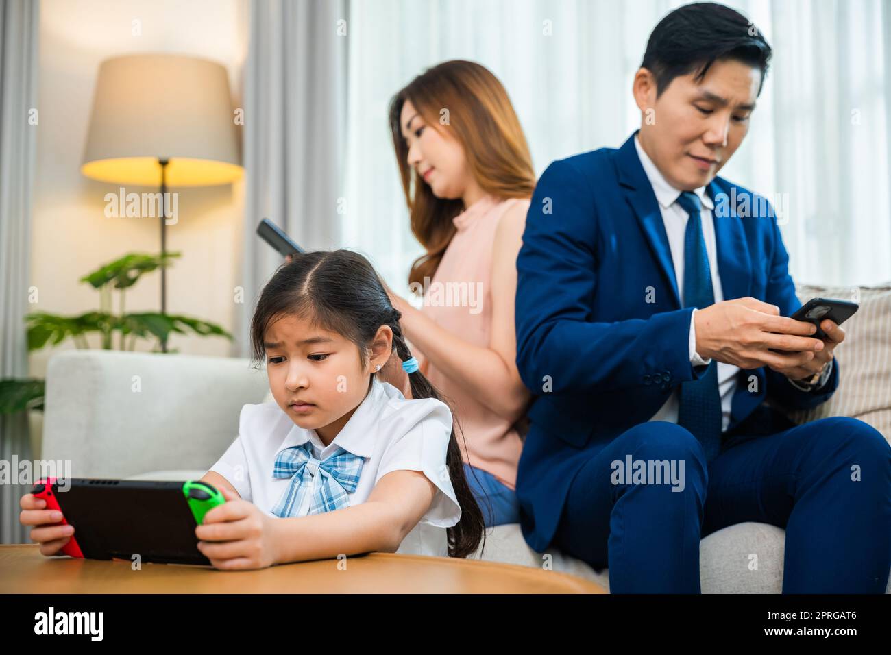 Asian parents ignore their child and looking at their mobile phone at ...