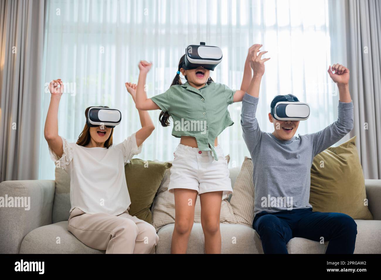 Asian family wear vr glasses headsets sitting on sofa in living room ...