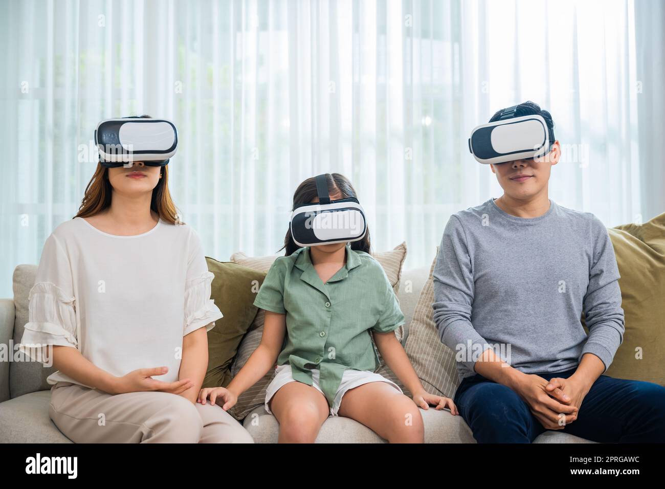 Asian family wear vr glasses headsets sitting on sofa in living room ...