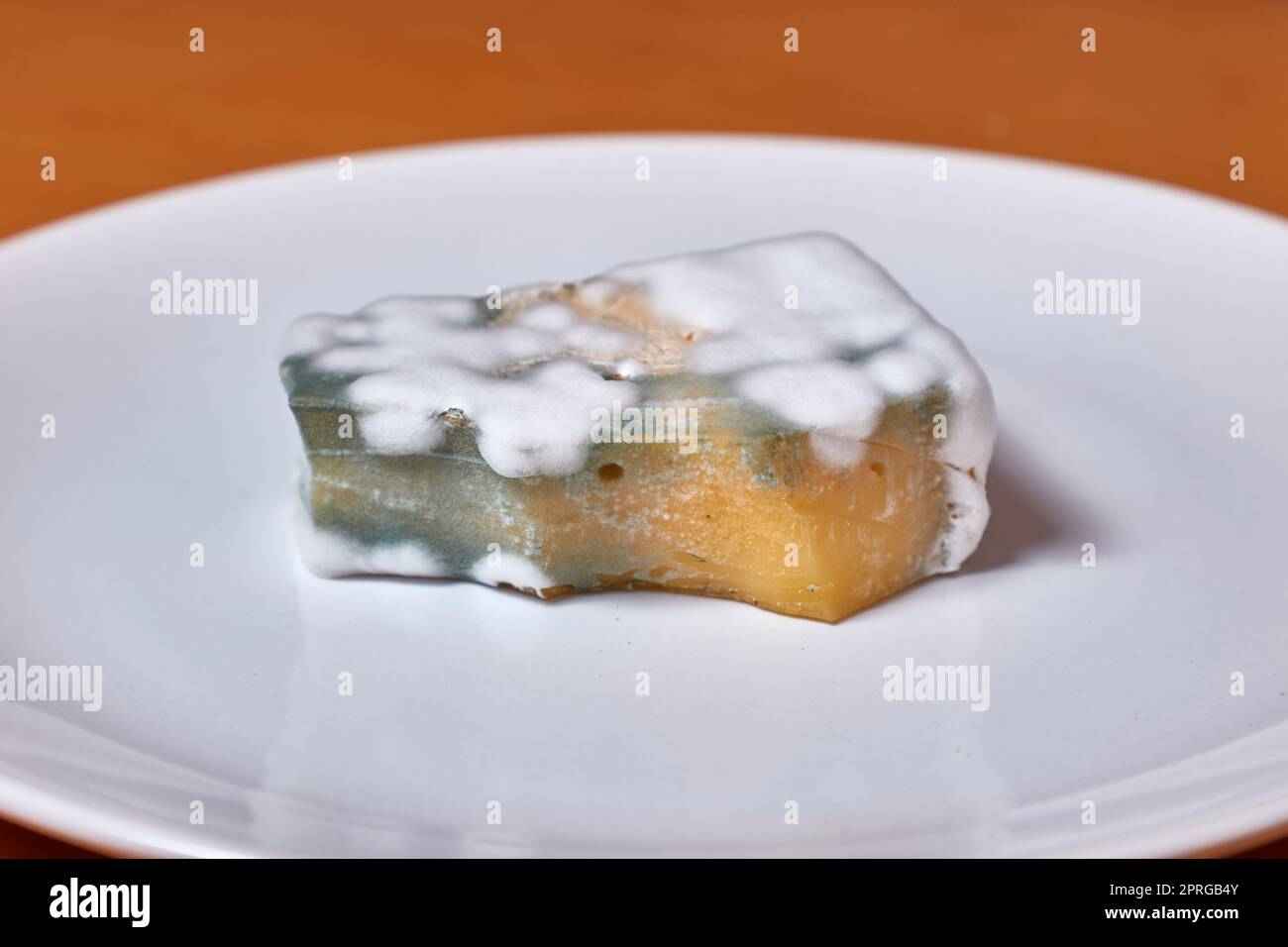 Expired moldy piece of cheese on a plate, mold growing Stock Photo - Alamy