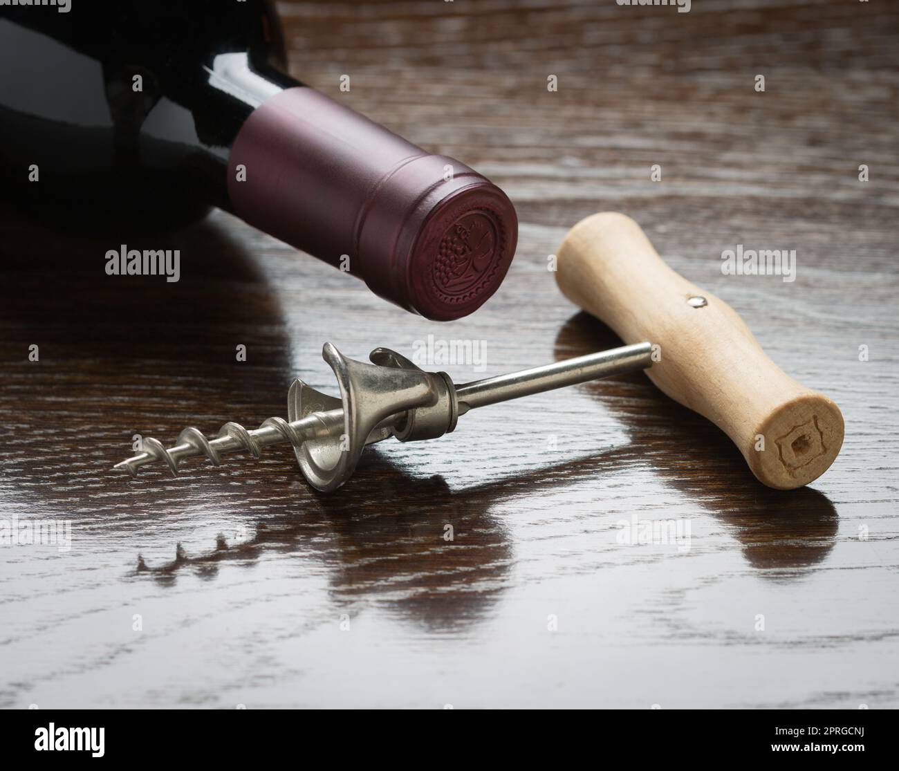 Abstract Wine Bottle and Corkscrew Laying on a Reflective Wood Surface ...