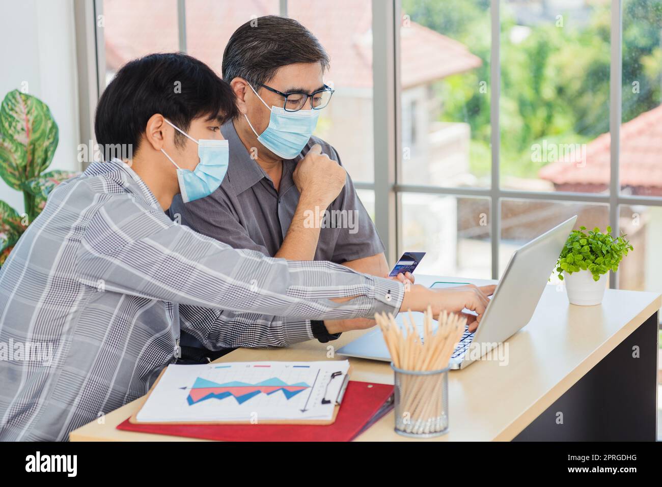 young man teaching senior father how to use credit card for shopping ...