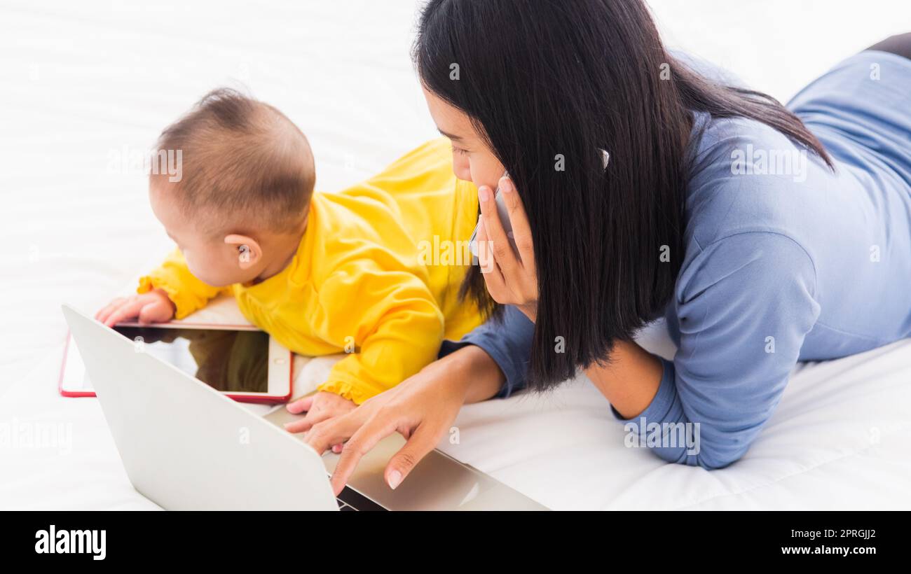 mother work from home busy with her baby daughter on laptop computer ...