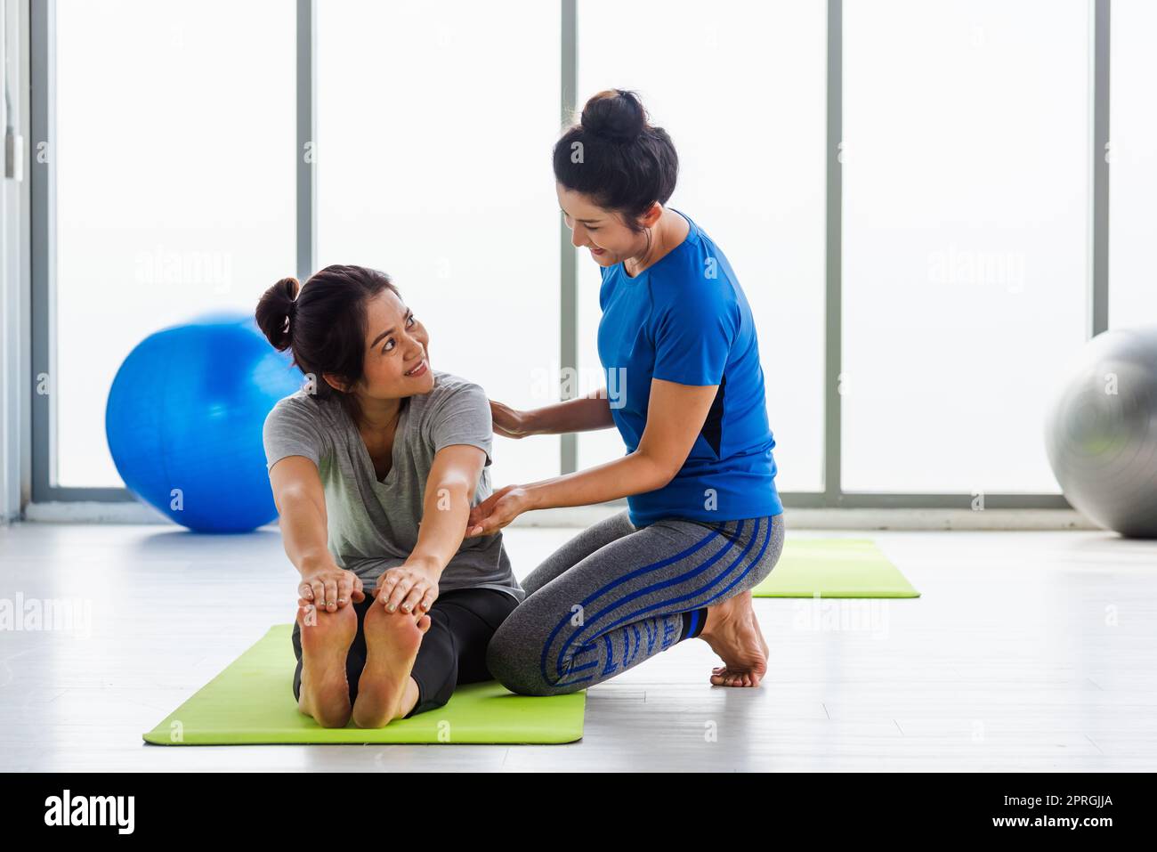 woman teacher teach adult student doing yoga stretching position in ...