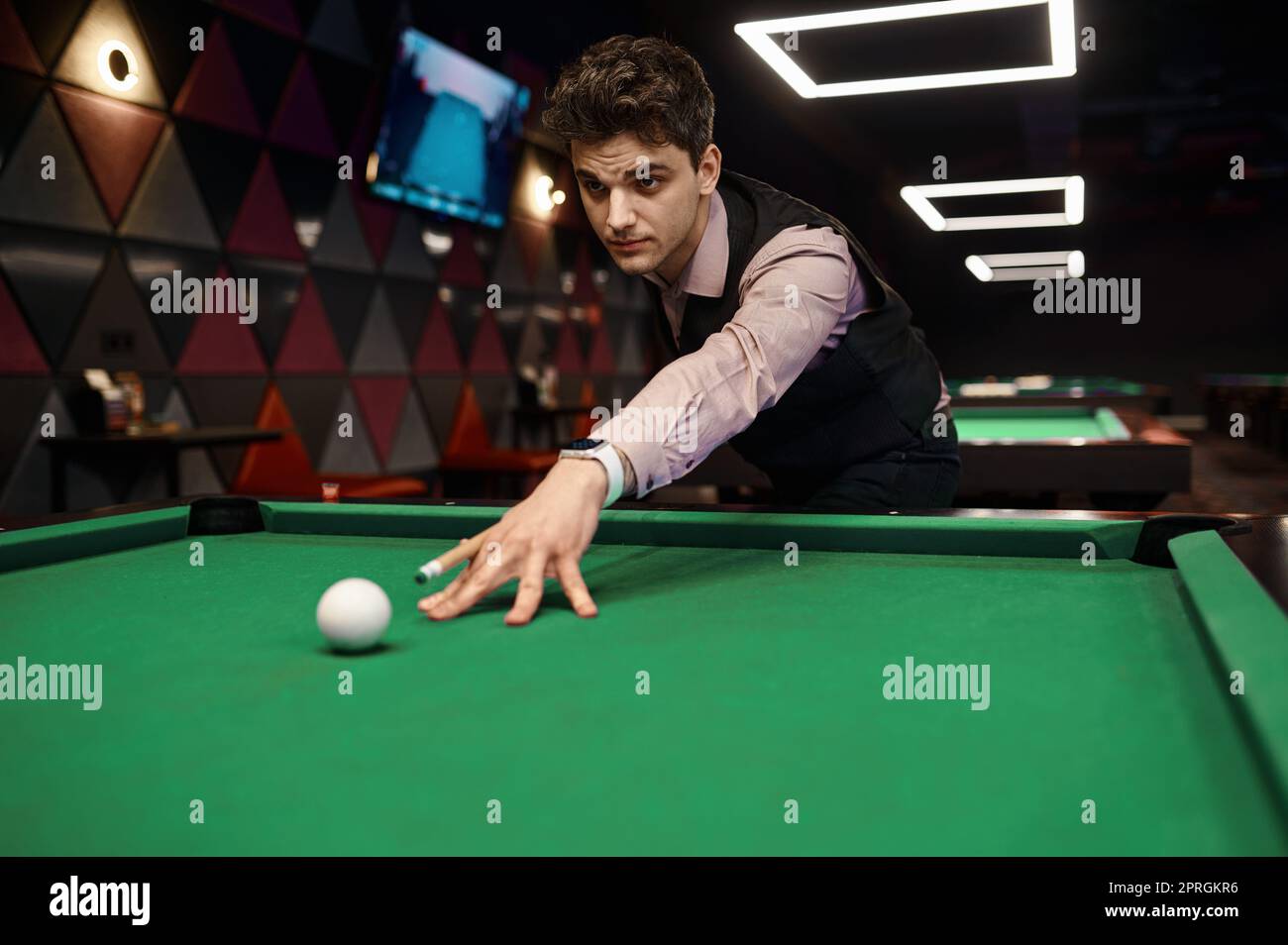 Portrait of young man aiming with billiards cue on white ball over game ...