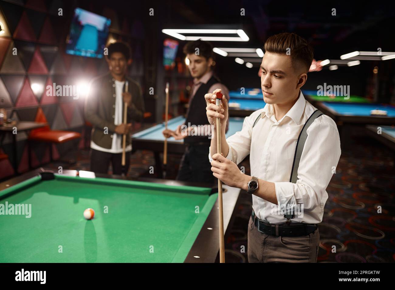 Young people friends or student playing billiards, focus on stylish guy ...