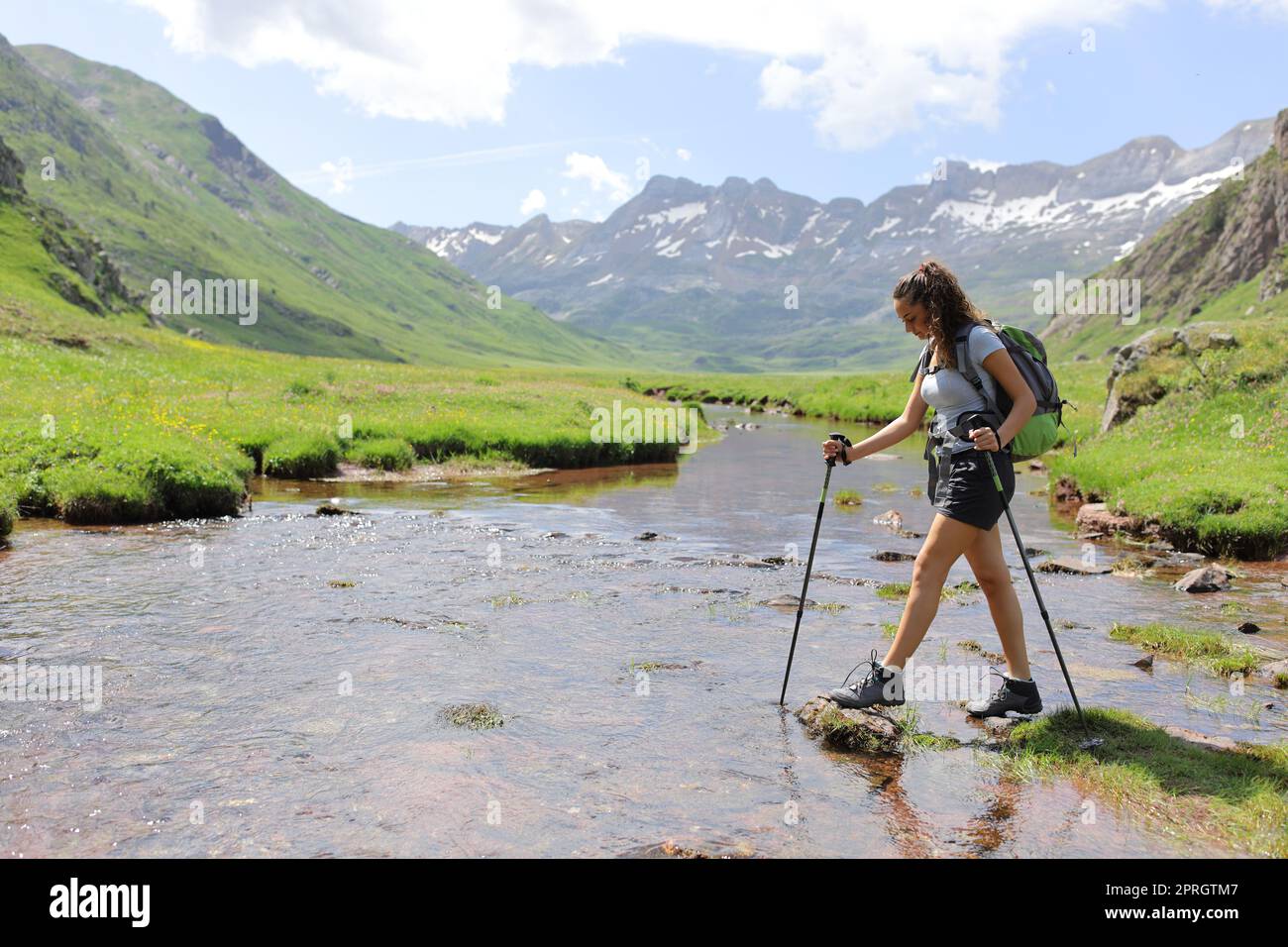 Full body portrait of a hiker ready to cross a river in the mountain ...