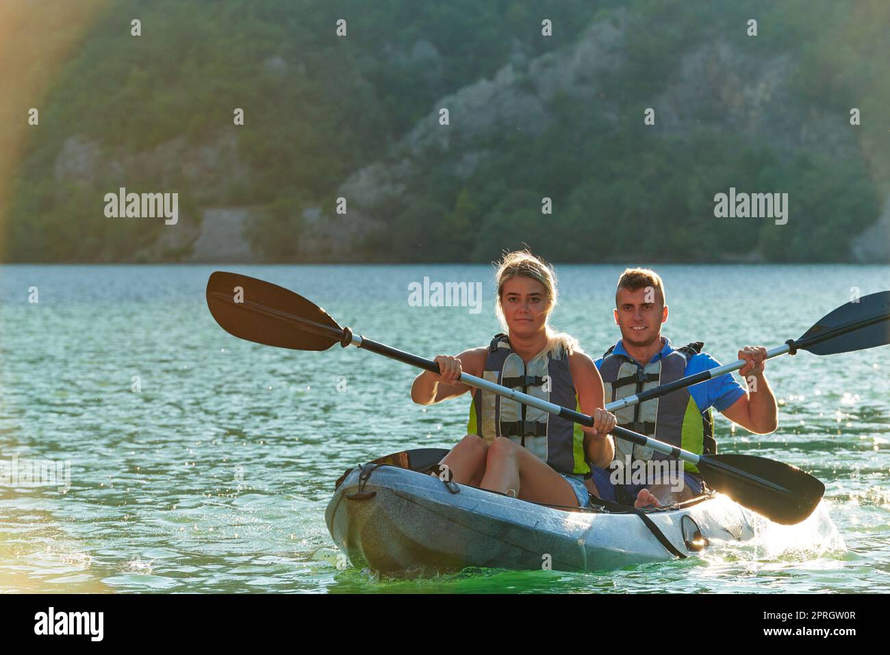 A young couple enjoying an idyllic kayak ride in the middle of a ...