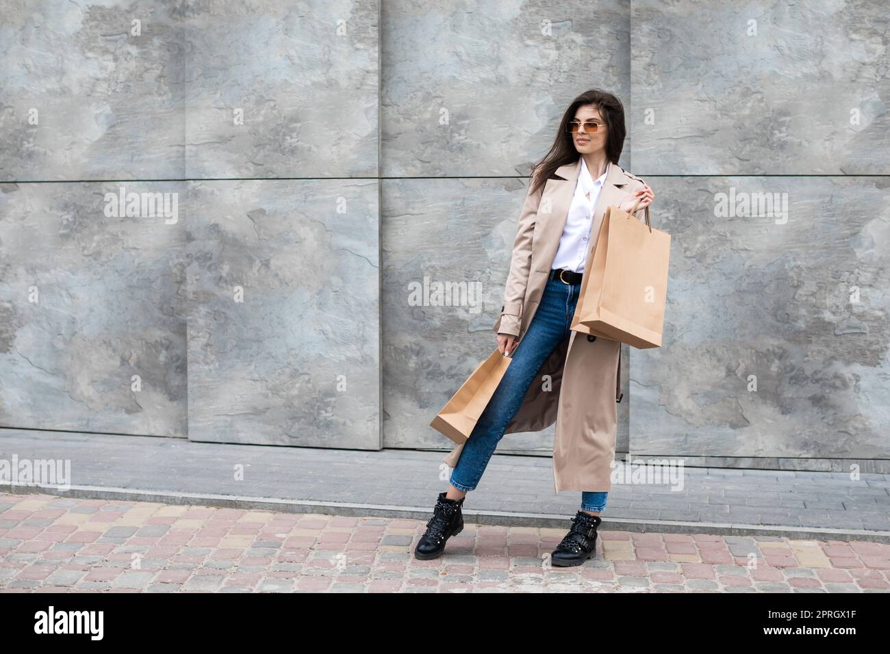 A girl in a casual clothes with shopping bags and lots of purchases ...