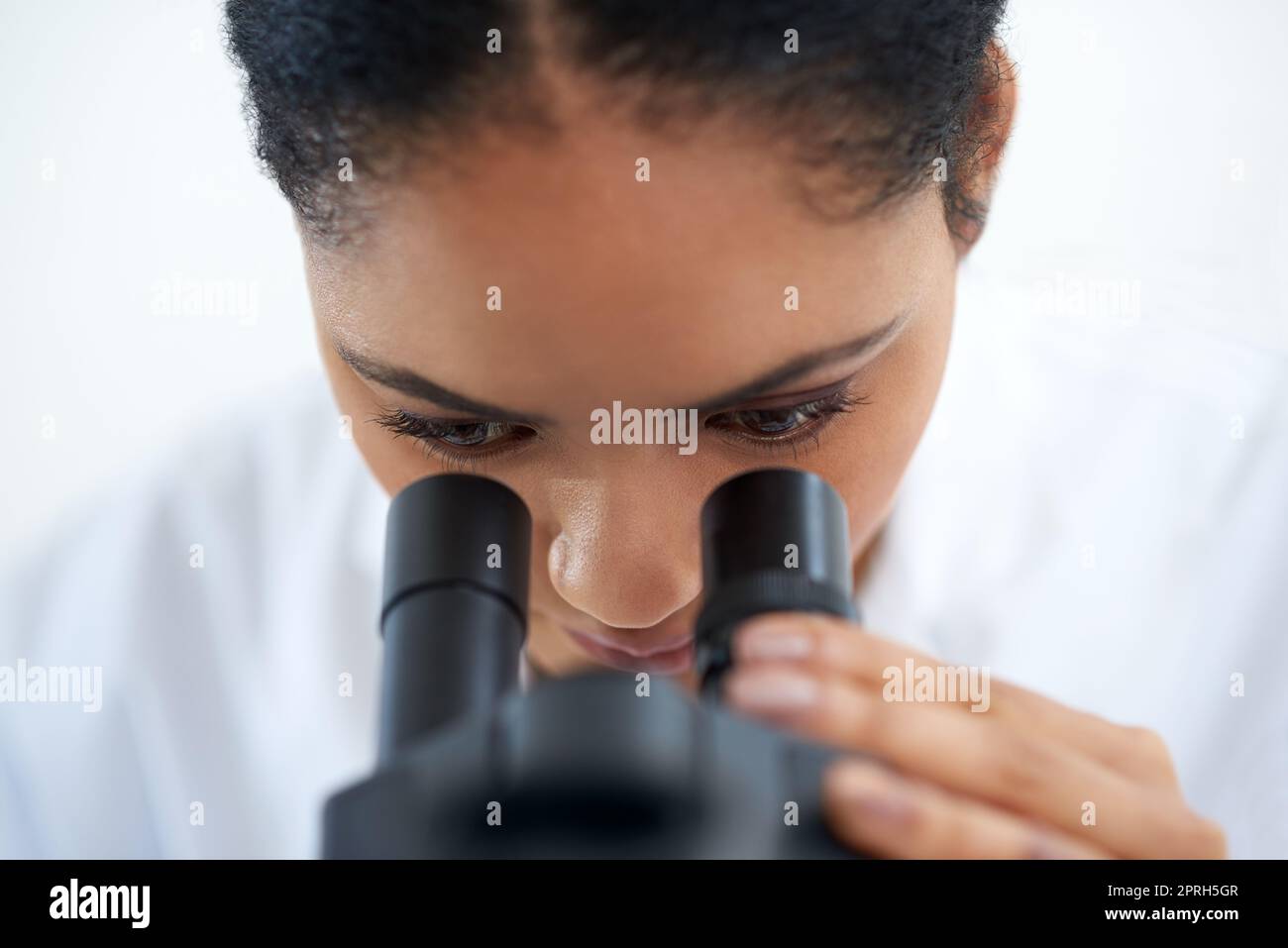 Through the microscope. an attractive young female scientist working in ...