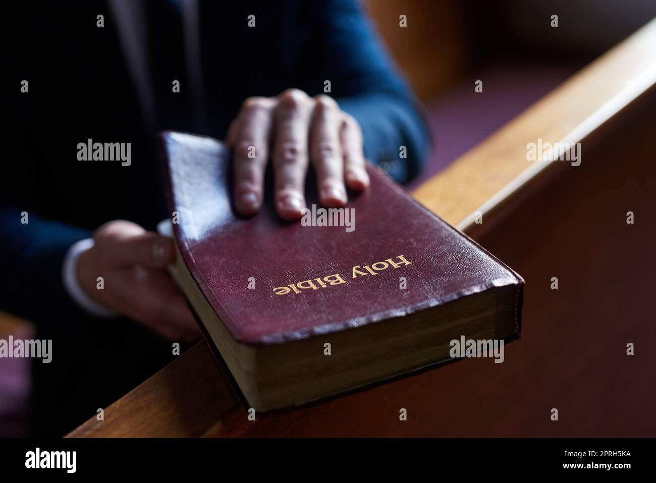 Reading the good book. a man opening a bible while sitting in a pew at ...