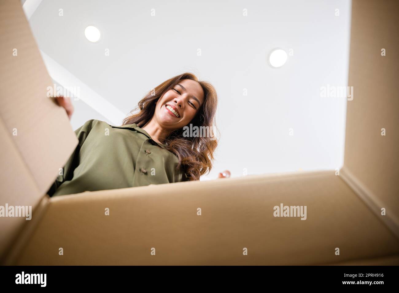 Happy Asian young woman opening carton box from internet store order ...