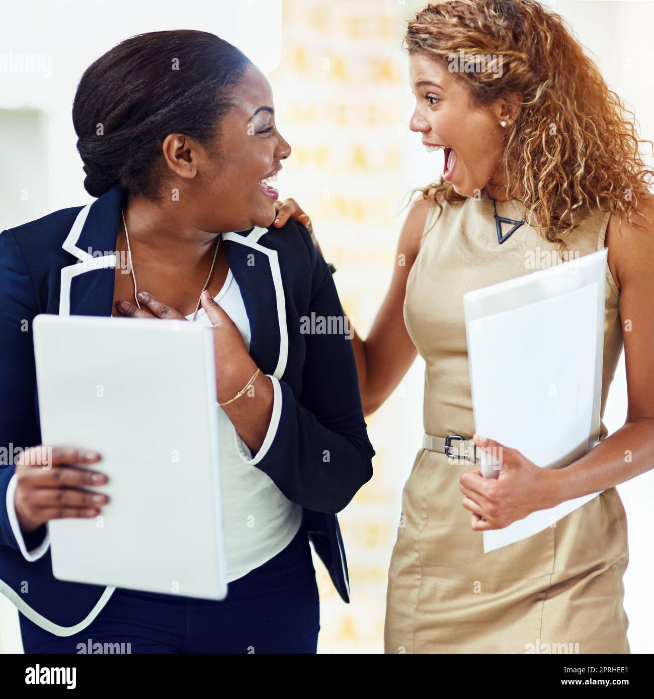 Sharing Laughs And Successes Two Female Coworkers Laughing Together In