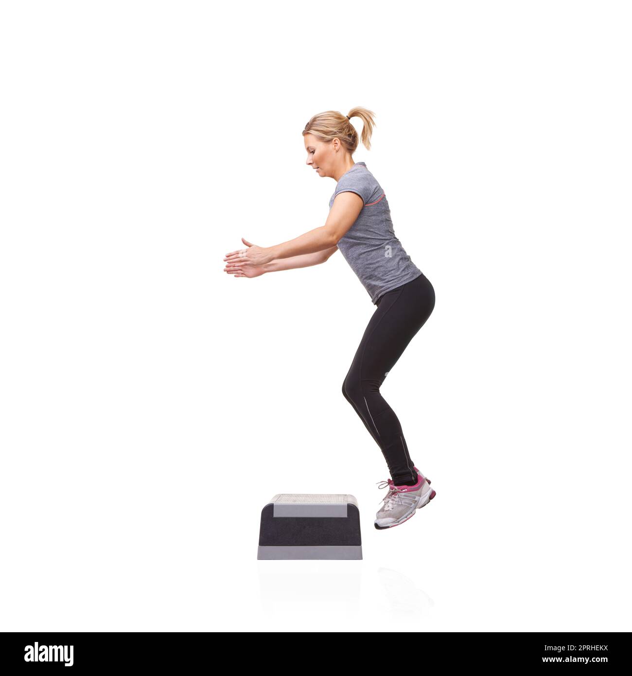 Leaping up in pursuit of fitness. A smiling young woman doing aerobics ...