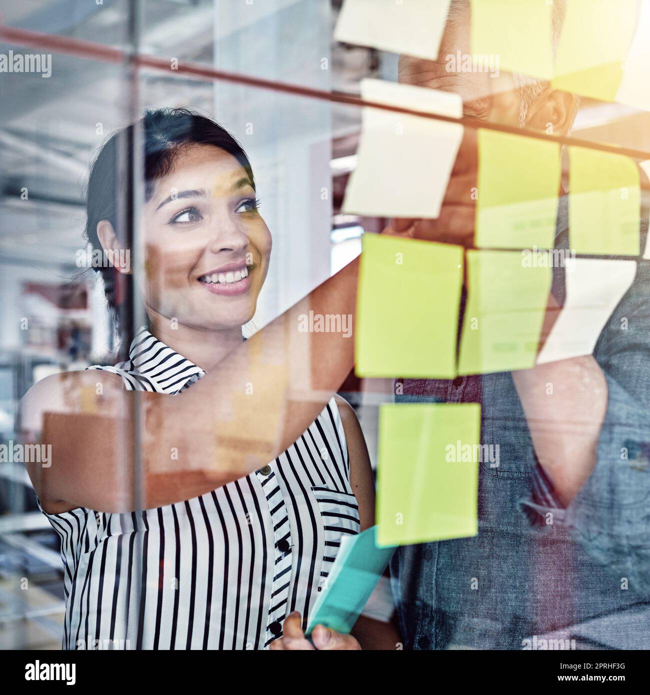 Organising their tasks. two colleagues looking at sticky notes on a ...