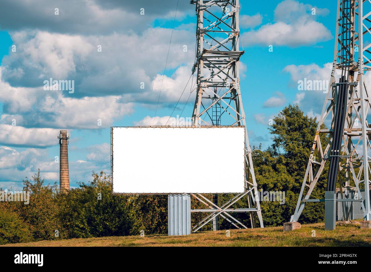 White canvas billboard next to high-voltage towers in industrial area ...