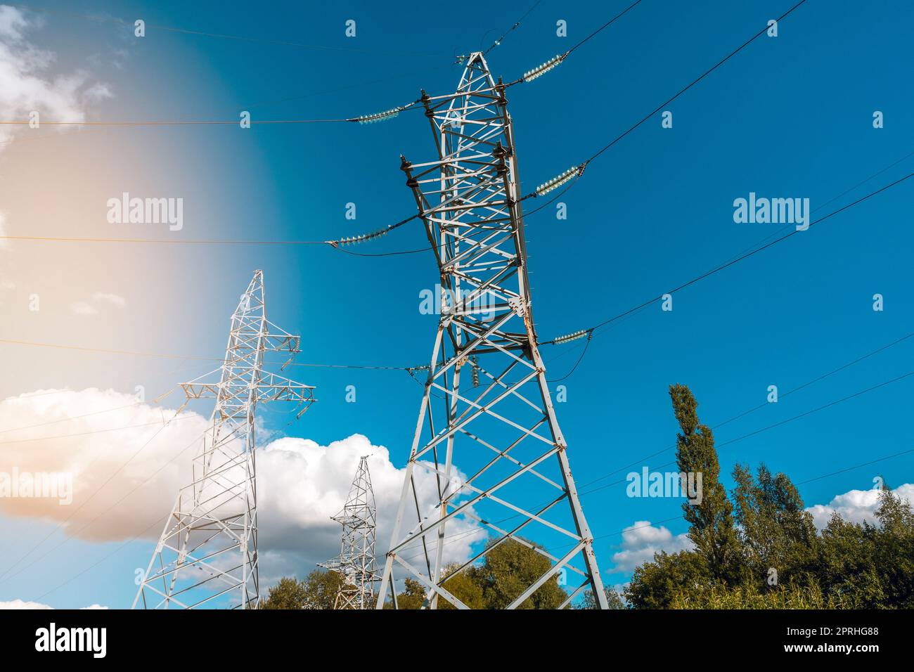 Low angle view of high voltage towers and electric cables against sunny ...