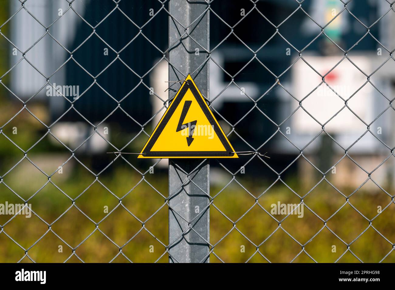 Yellow triangle with lightning on metal fence Stock Photo - Alamy