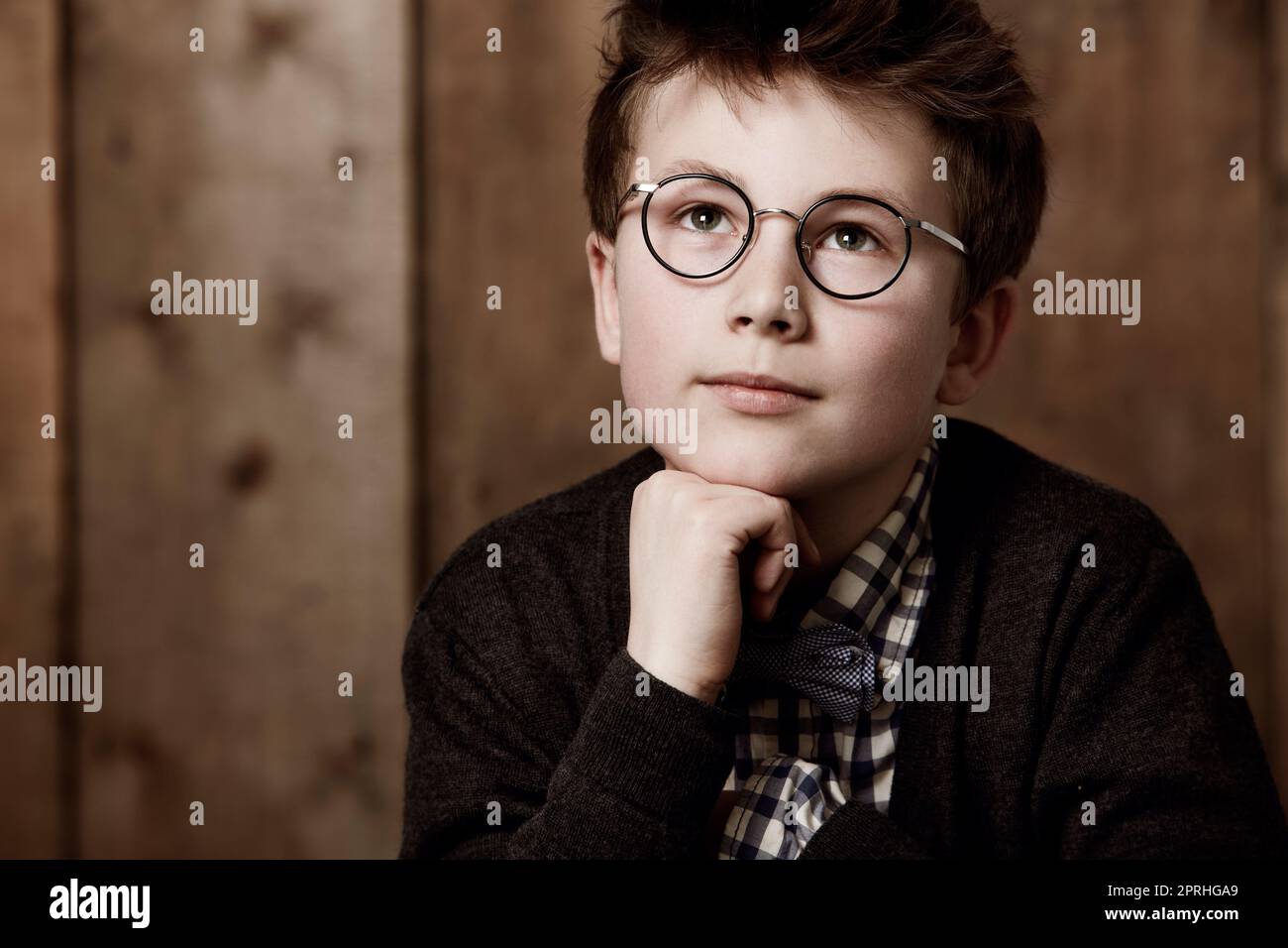 Thoughts of his future. Young boy wearing spectacles with a thoughtful ...