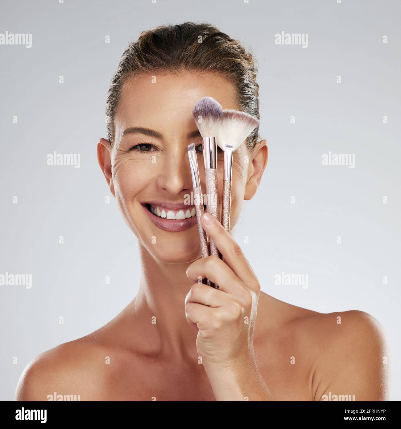 Mature, model and brush for makeup in hand by face with happiness for ...