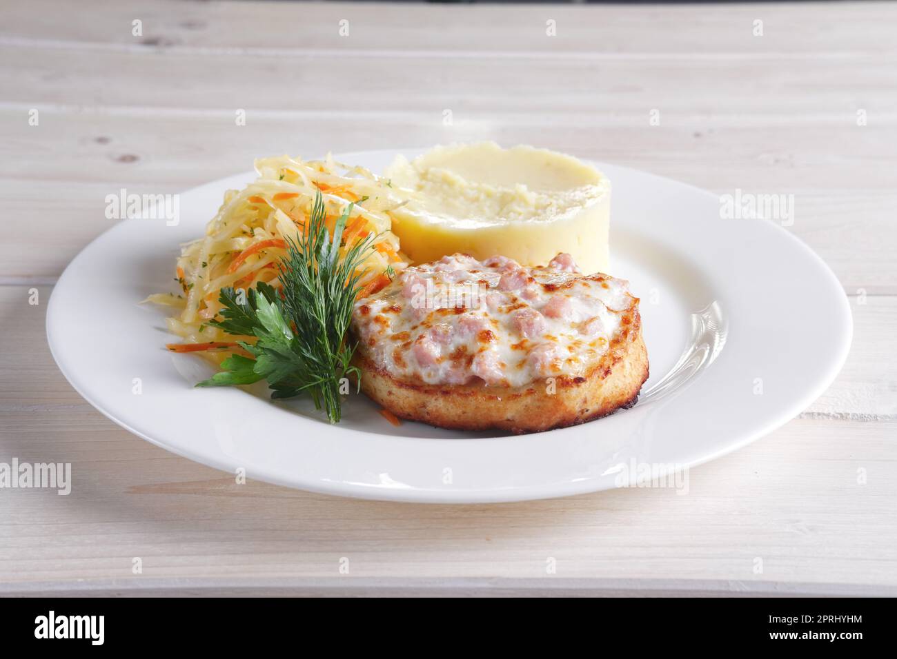 Fish cutlet with ham and melted cheese topping served with pickled ...