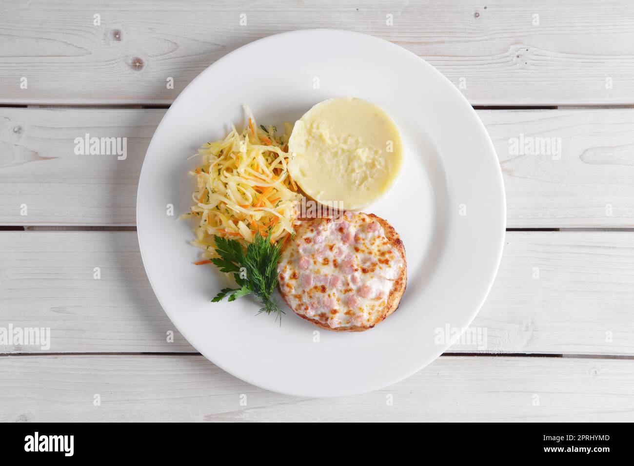Fish cutlet with ham and melted cheese topping served with pickled ...