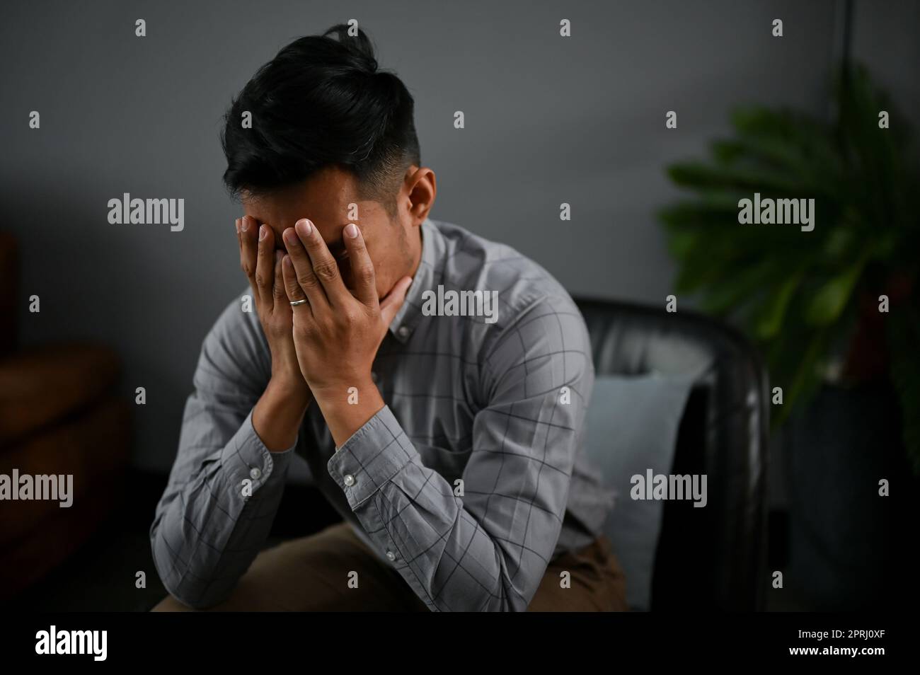 Stressed and depressed millennial Asian man is covering his face ...
