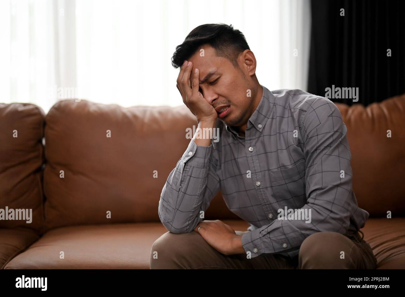 Stressed and upset millennial Asian man is covering his face, crying ...