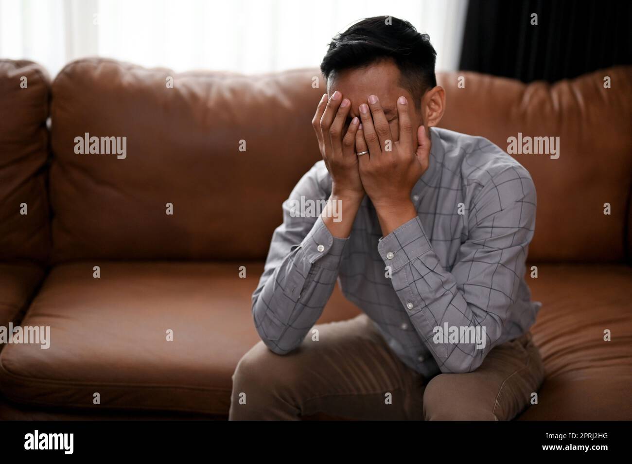 Stressed and depressed millennial Asian man is covering his face ...