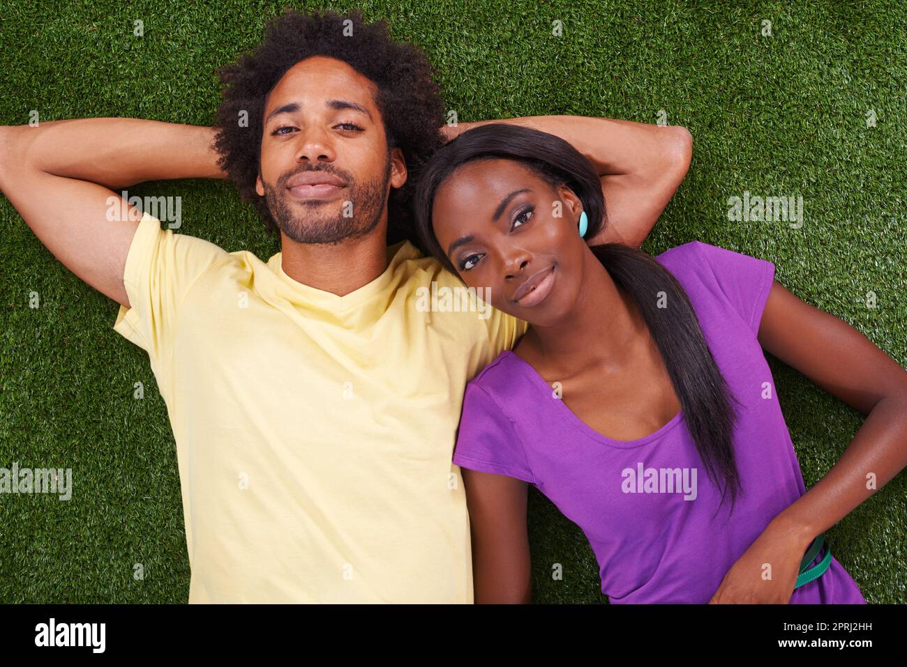 Just unwinding together. A young african couple lying on the grass ...