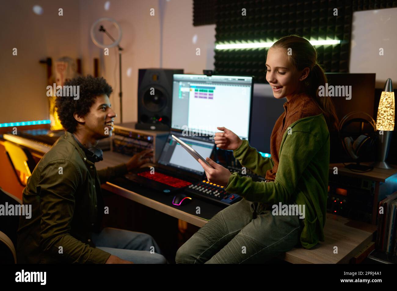 Audio engineer with young girl singer working in music recording studio ...